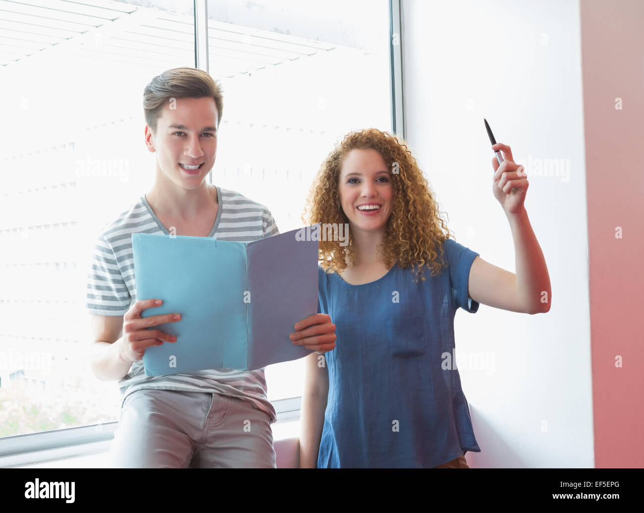 Smiling student holding notebook and pen Stock Photo - Alamy