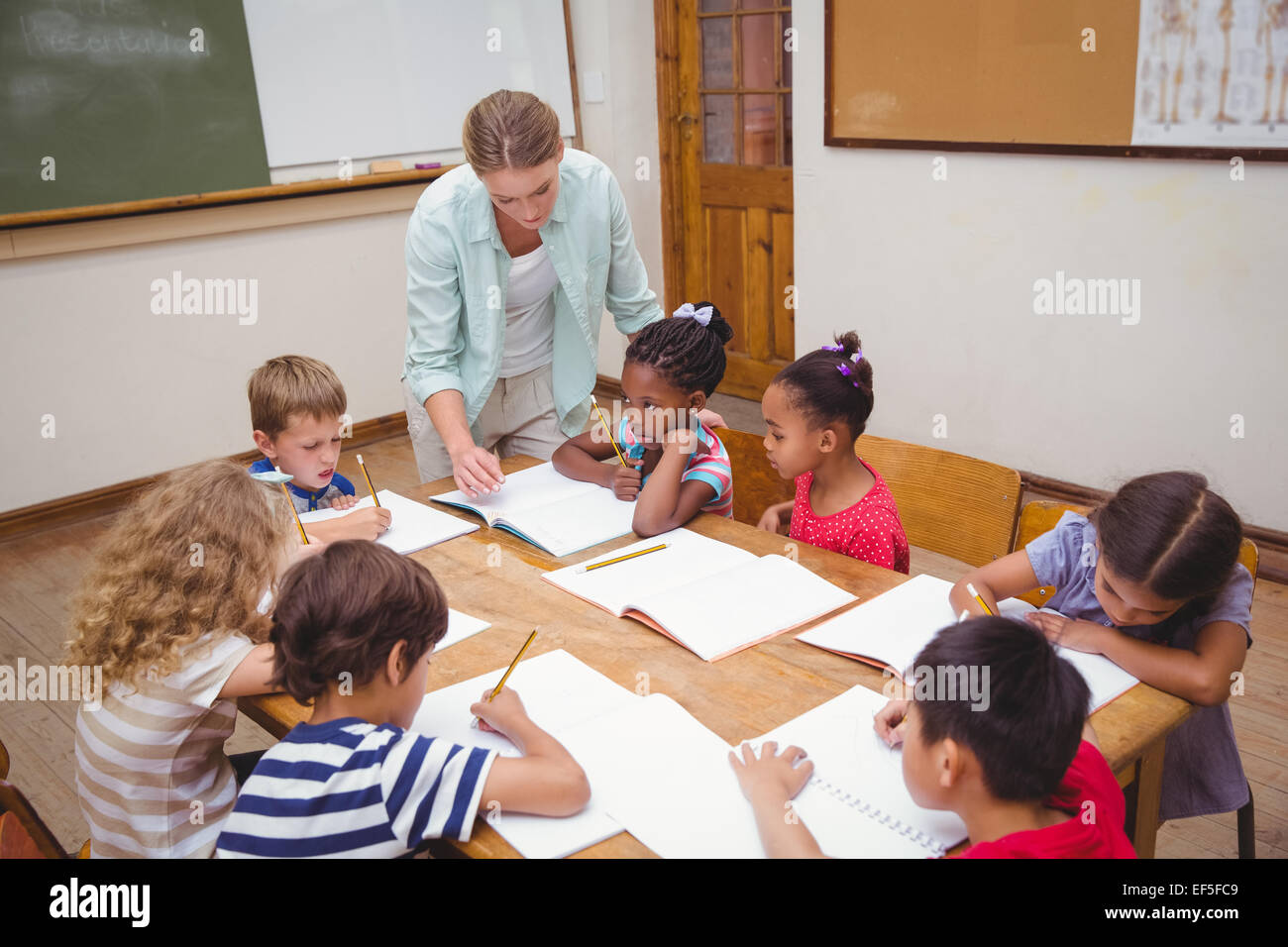 Teacher and pupils working at desk together Stock Photo - Alamy