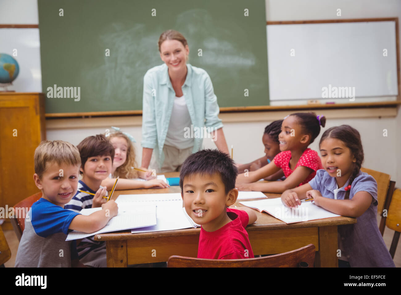 Teacher and pupils working at desk together Stock Photo - Alamy