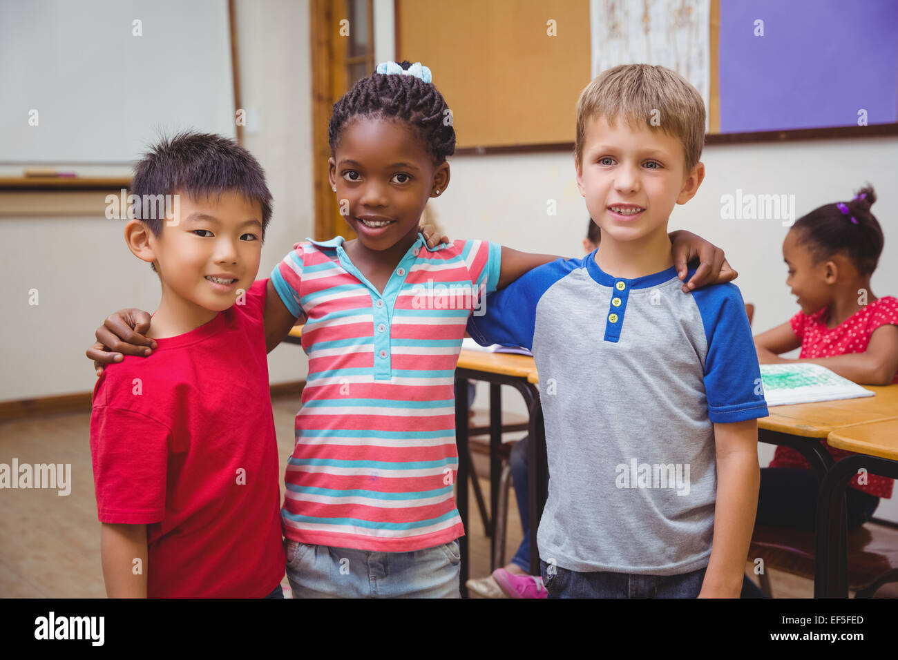 Cute pupils smiling at camera in classroom Stock Photo - Alamy