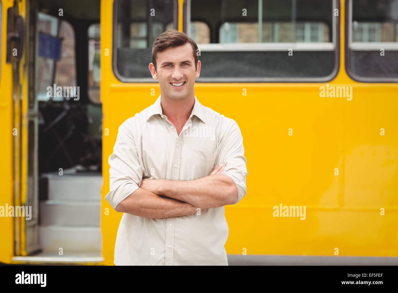 Smiling bus driver standing with arms crossed Stock Photo - Alamy