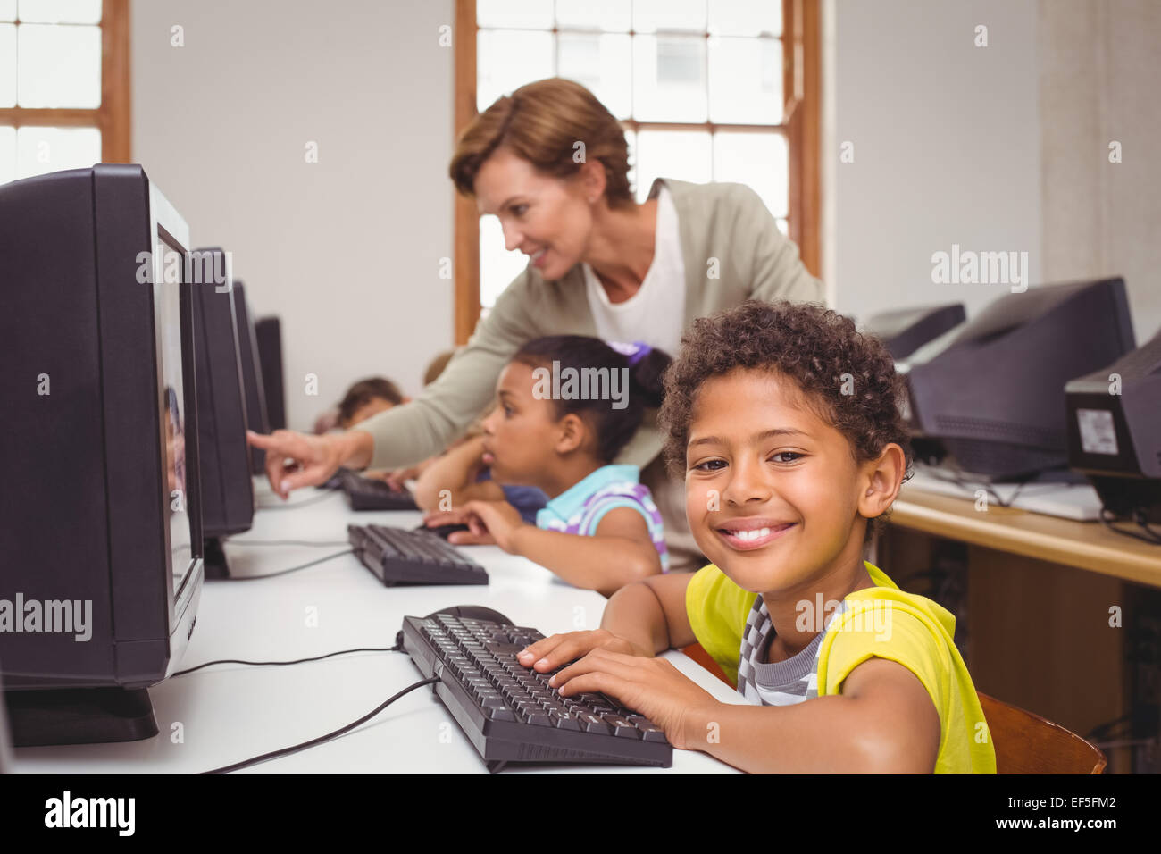 Cute pupil in computer class smiling at camera Stock Photo - Alamy