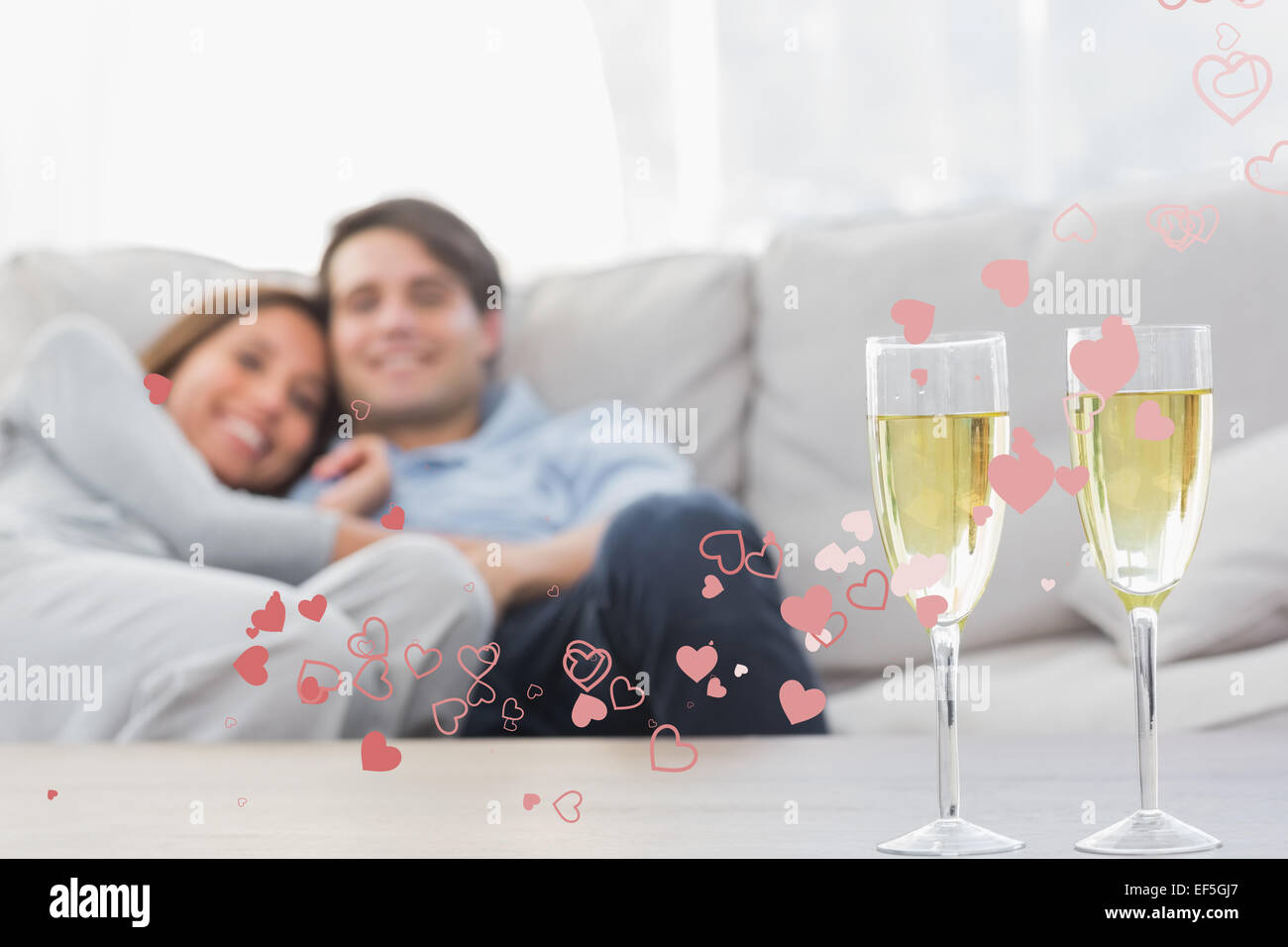 Composite image of couple resting on a couch with flutes of champagne ...