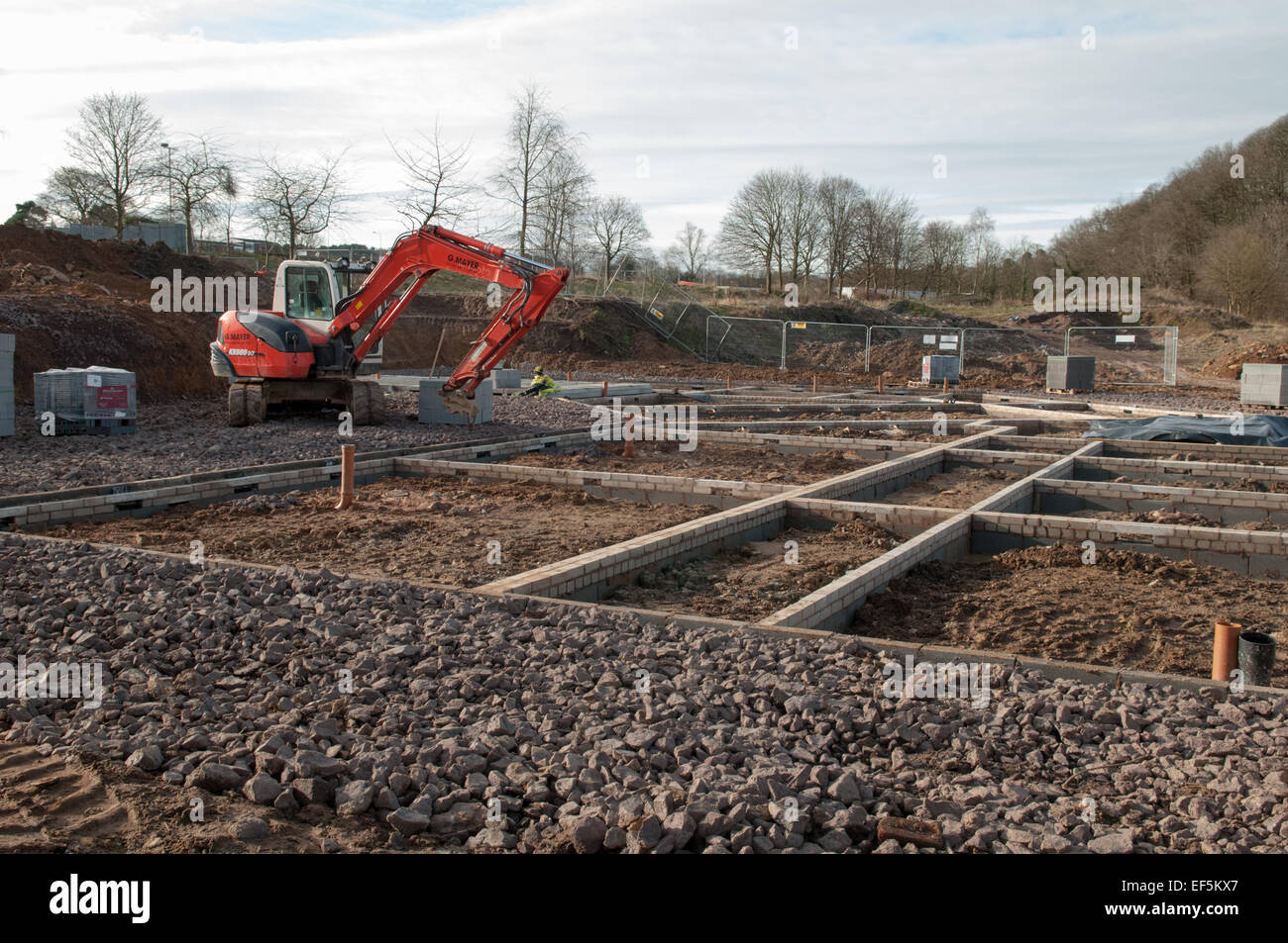 An empty building site with a digger and a pile of breeze blocks ...