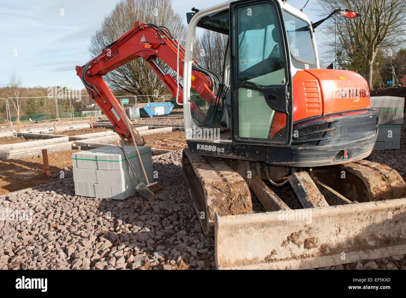 An empty building site with a digger and a pile of breeze blocks ...