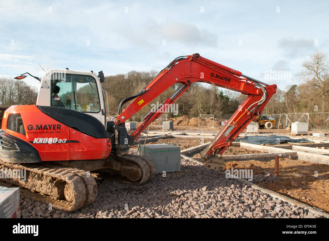 An empty building site with a digger and a pile of breeze blocks ...