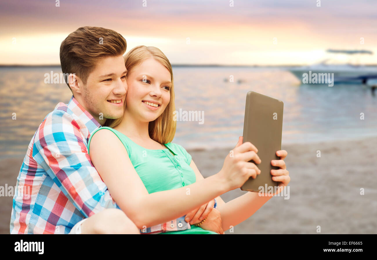 couple with tablet pc taking selfie over beach Stock Photo - Alamy