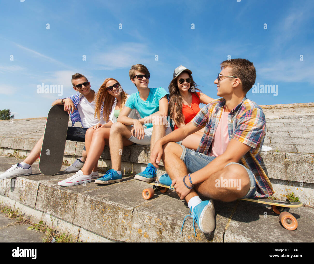 group of smiling friends sitting on city street Stock Photo - Alamy