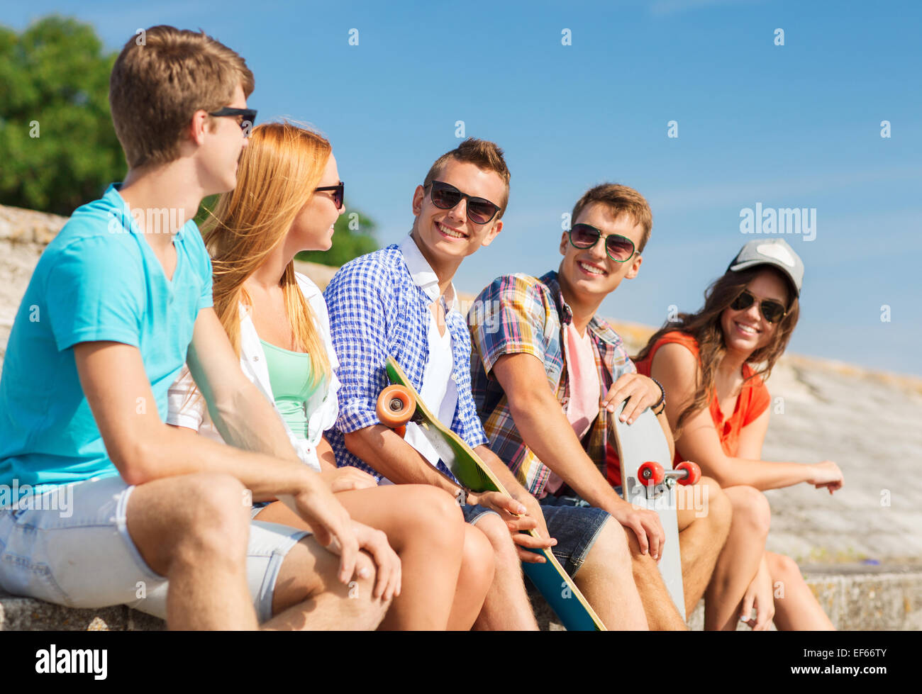 group of smiling friends sitting on city street Stock Photo - Alamy