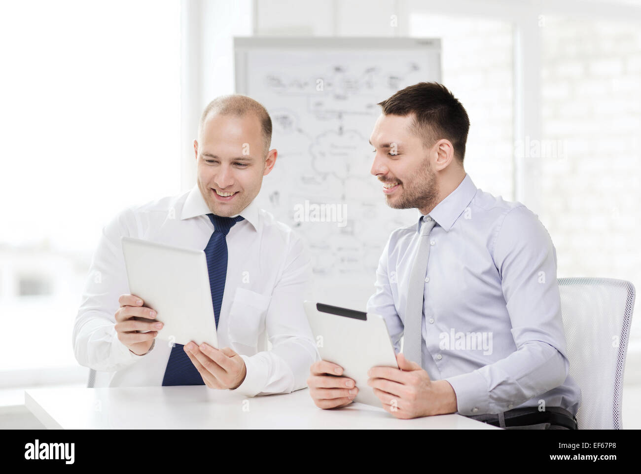 two smiling businessmen with tablet pc in office Stock Photo - Alamy