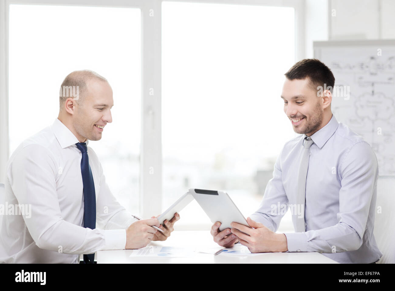 two smiling businessmen with tablet pc in office Stock Photo - Alamy