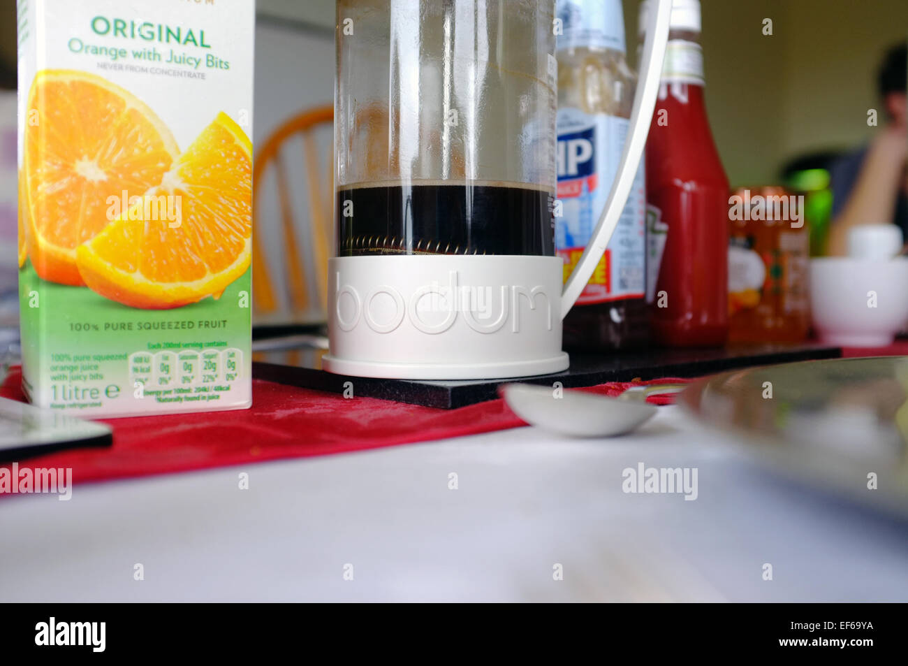 A white bodum cafetiere on a breakfast table with orange juice and ...