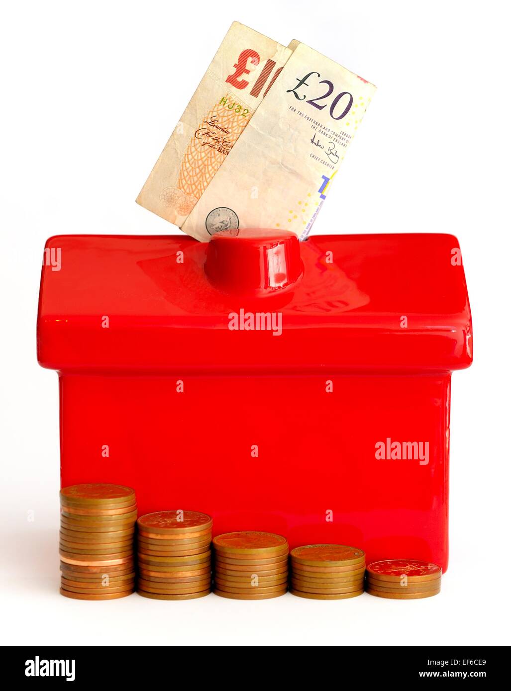 A red house money box with small stacks of coins in front and notes on ...