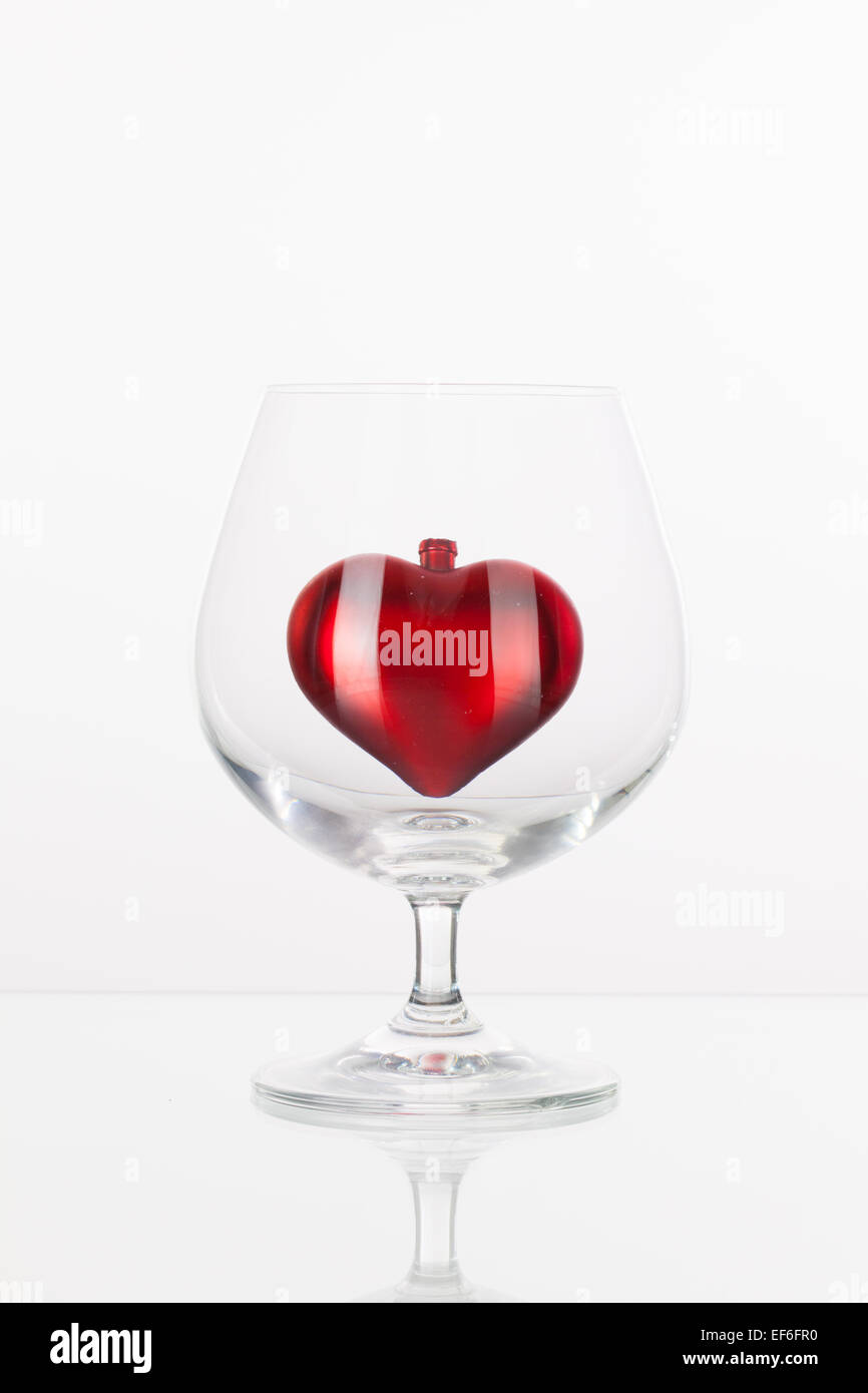 Red heart inside a glass of cognac on a glass plate Stock Photo - Alamy
