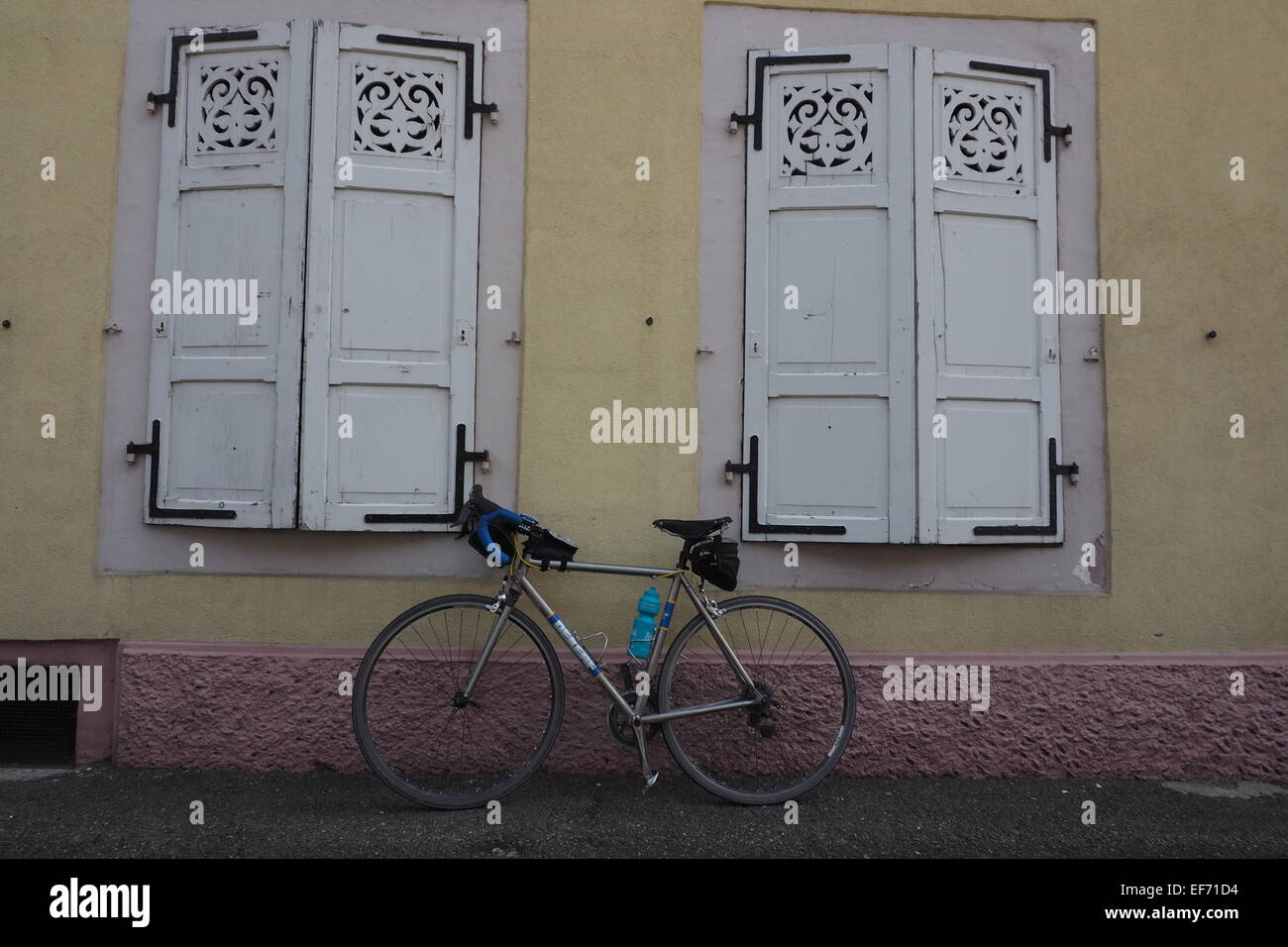 A bicycle resting against a wall under tow shuttered windows Stock ...