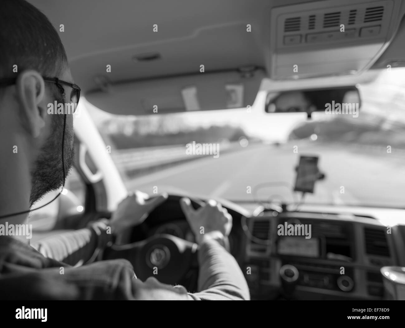 Black and white shot of a man behind the wheel, driving car in a ...