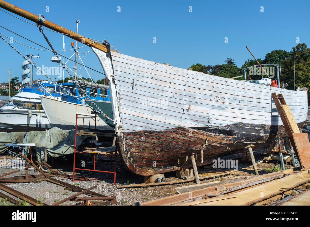Old clinker built sailing boat being repaired in a boatyard on Exeter ...