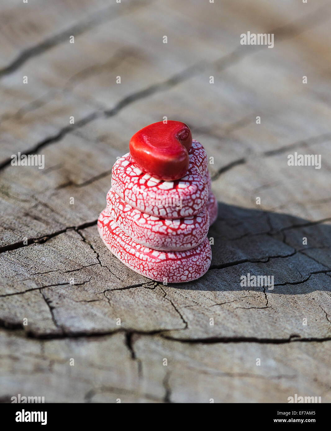 A pink and red ceramic hearts pyramid is placed on a flat wooden ...
