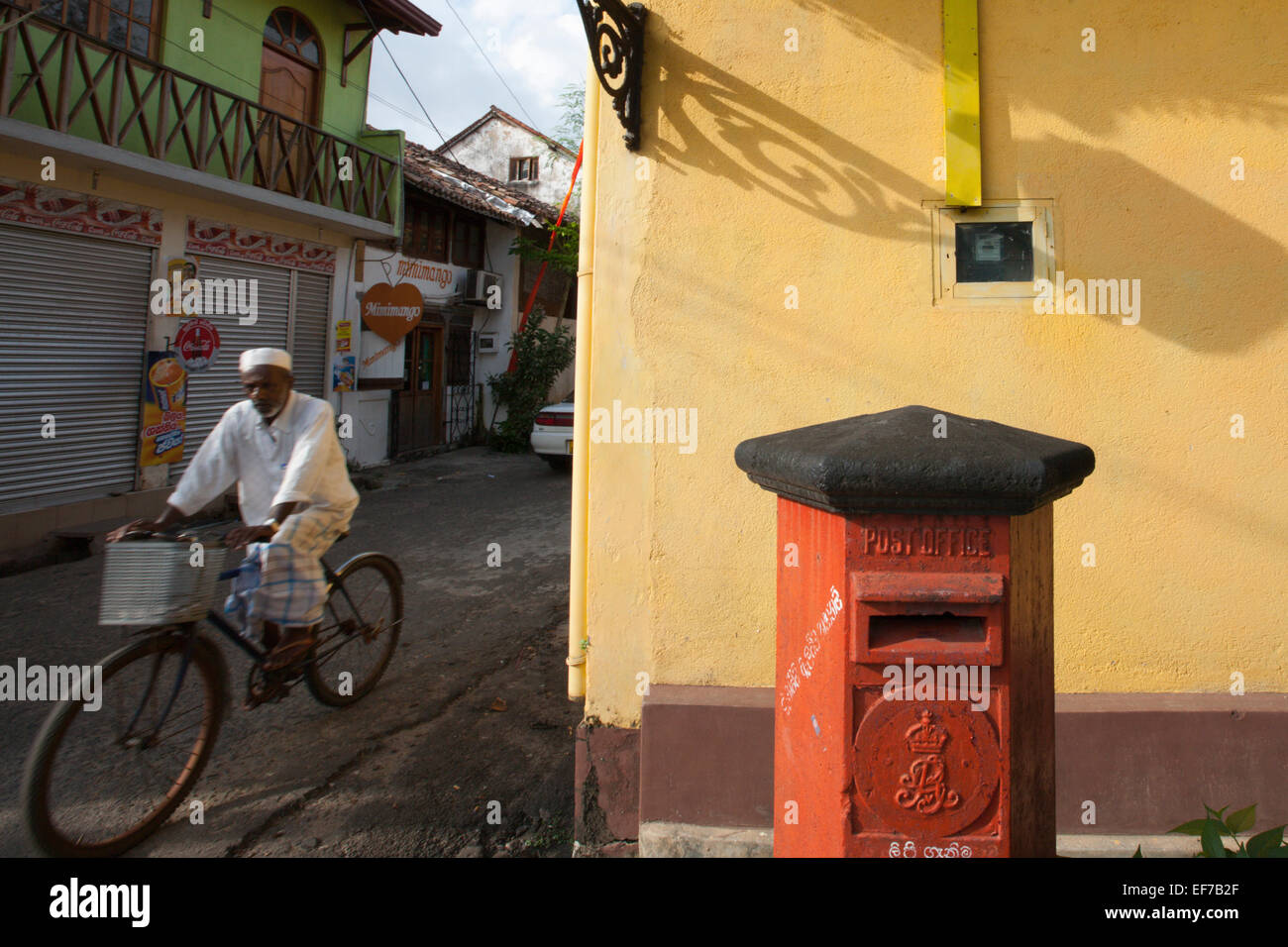 MUSLIM MAN CYCLING PAST COLONIAL POST BOX ON COLONIAL STREET IN GALLE ...
