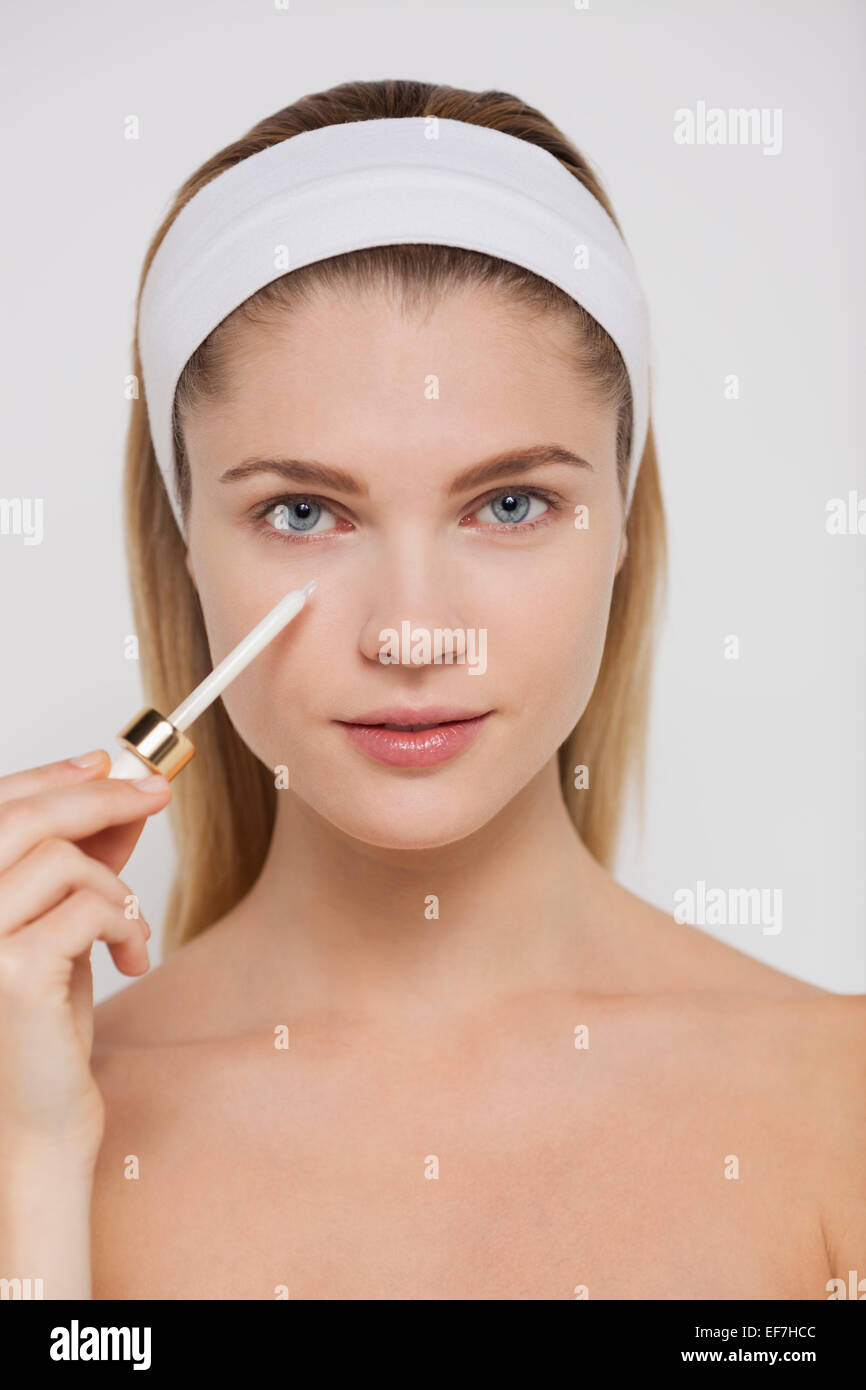 Beautiful woman applying foundation on her face Stock Photo - Alamy