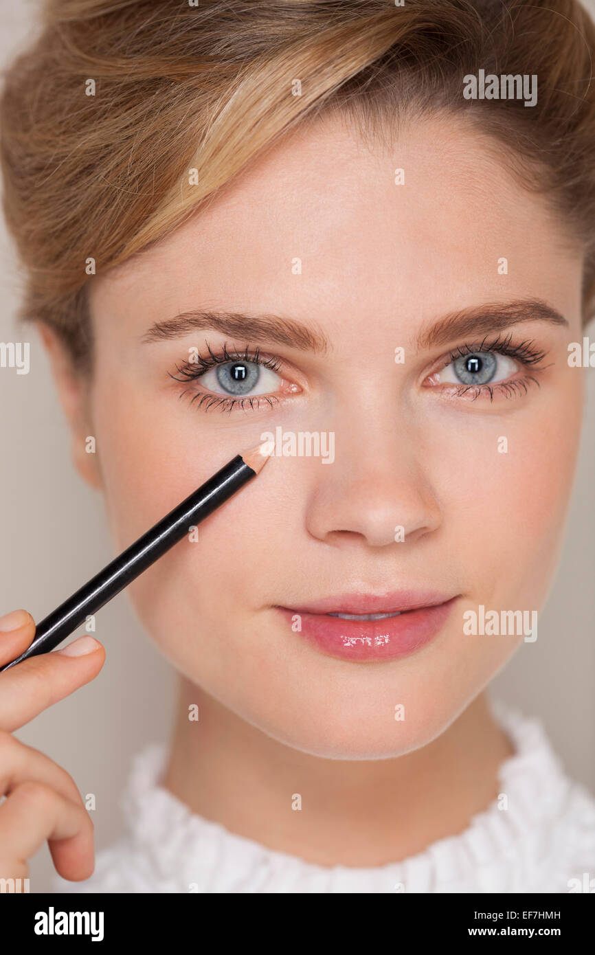 Portrait of beautiful woman applying concealer Stock Photo - Alamy