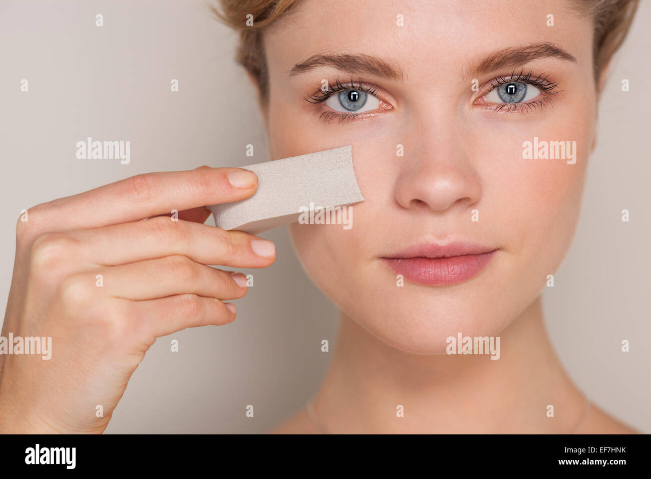 Beautiful woman using sponge on face Stock Photo - Alamy