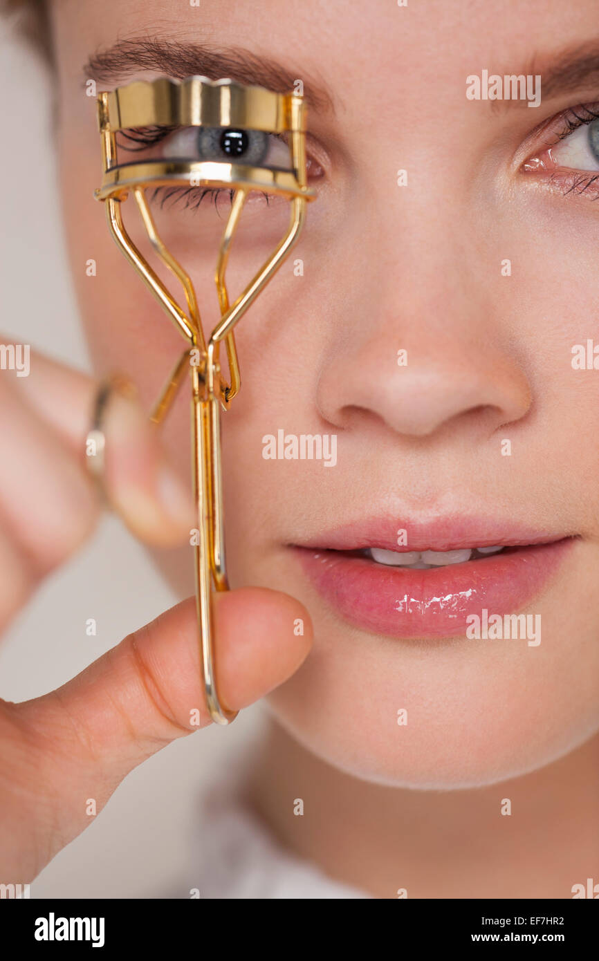 Young woman curling her eyelashes with a curler Stock Photo - Alamy