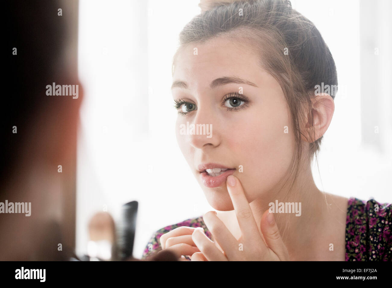 Teenage girl looking her face on mirror Stock Photo - Alamy