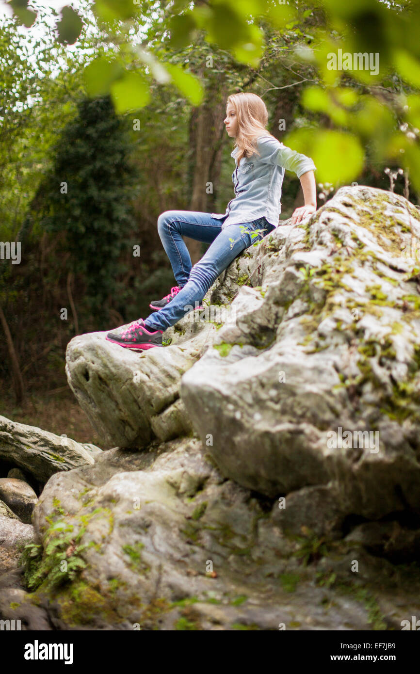 Girl sitting on rock in a park Stock Photo - Alamy