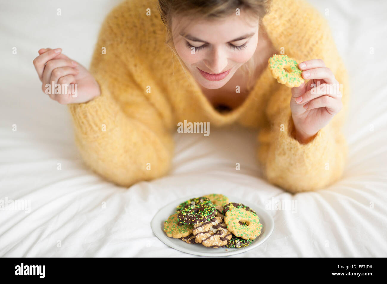 Woman eating a cookie on bed Stock Photo - Alamy