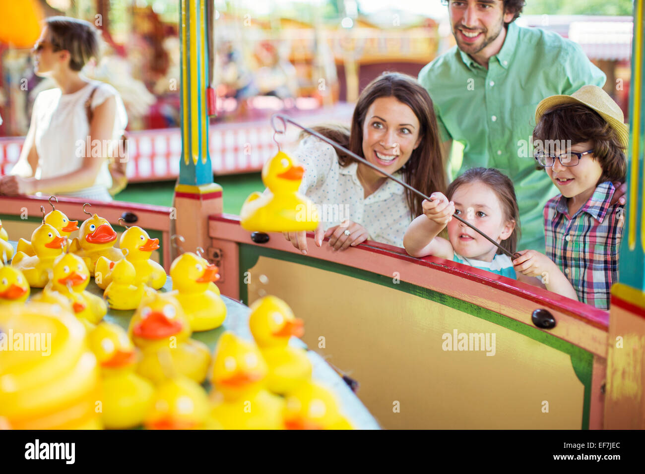 Parents with two children having fun with fishing game in amusement ...