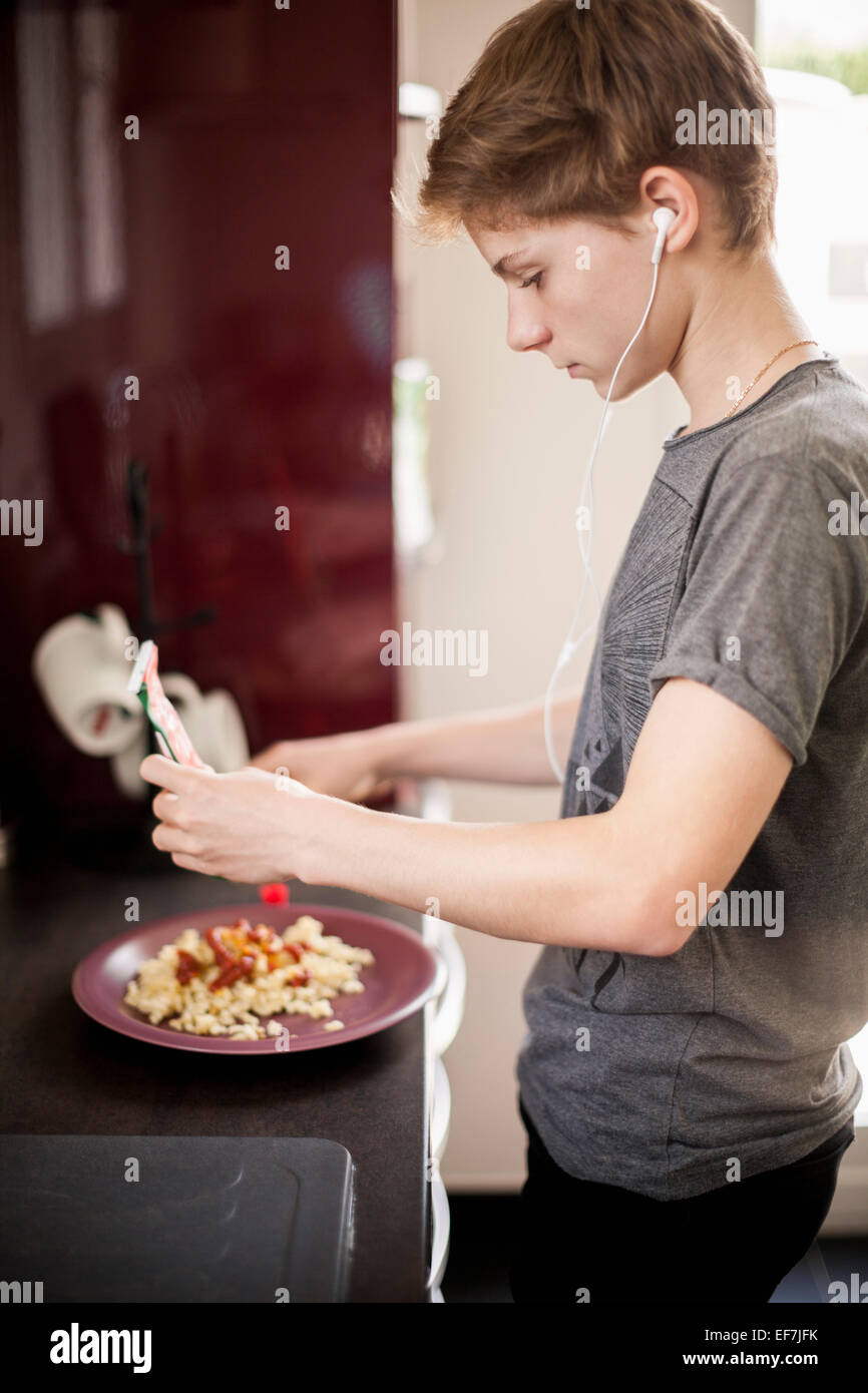 Teenage boy listening to music with breakfast Stock Photo - Alamy