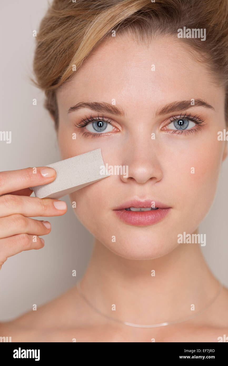 Beautiful woman using sponge on face Stock Photo - Alamy