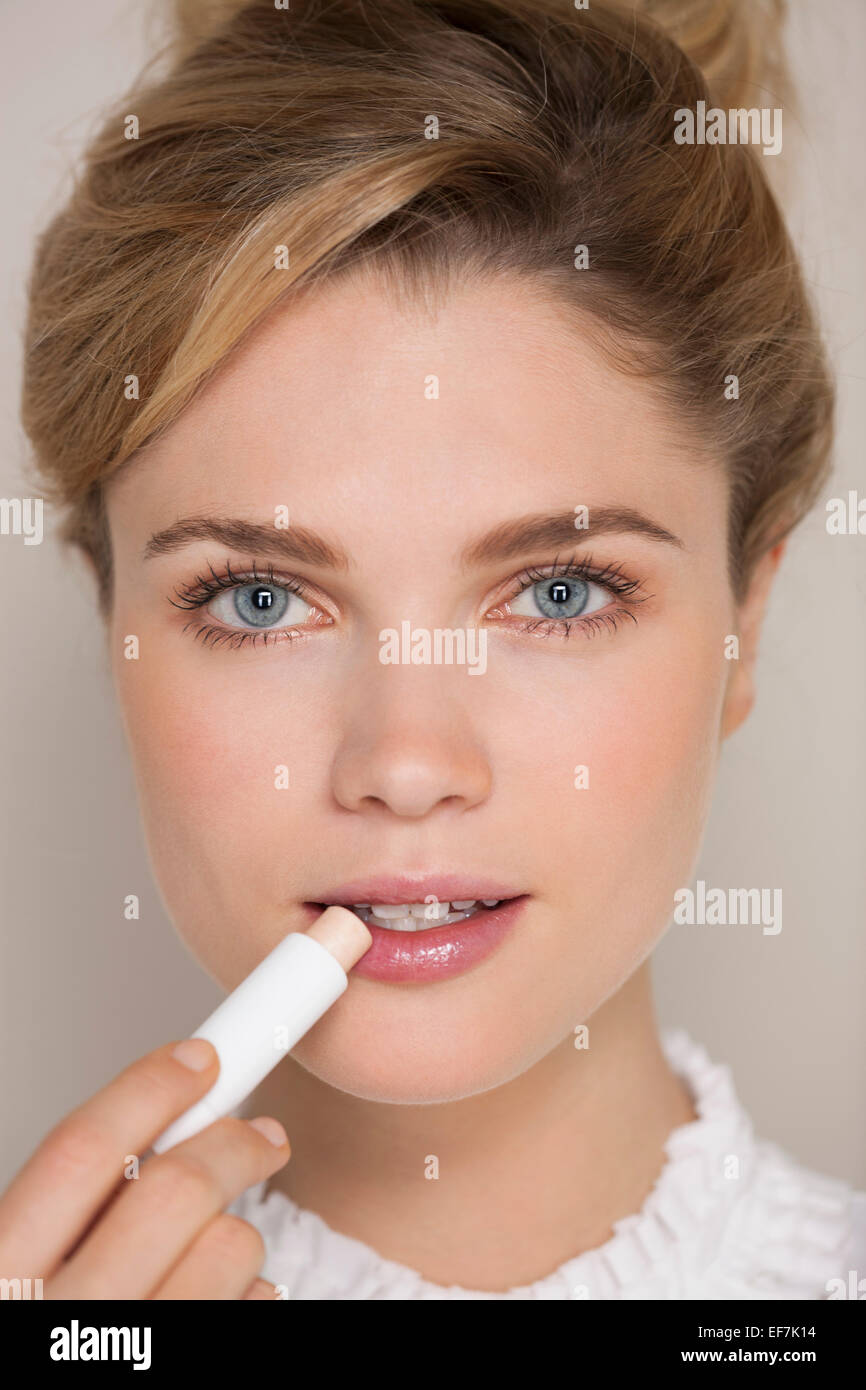 Beautiful woman applying lip balm Stock Photo - Alamy