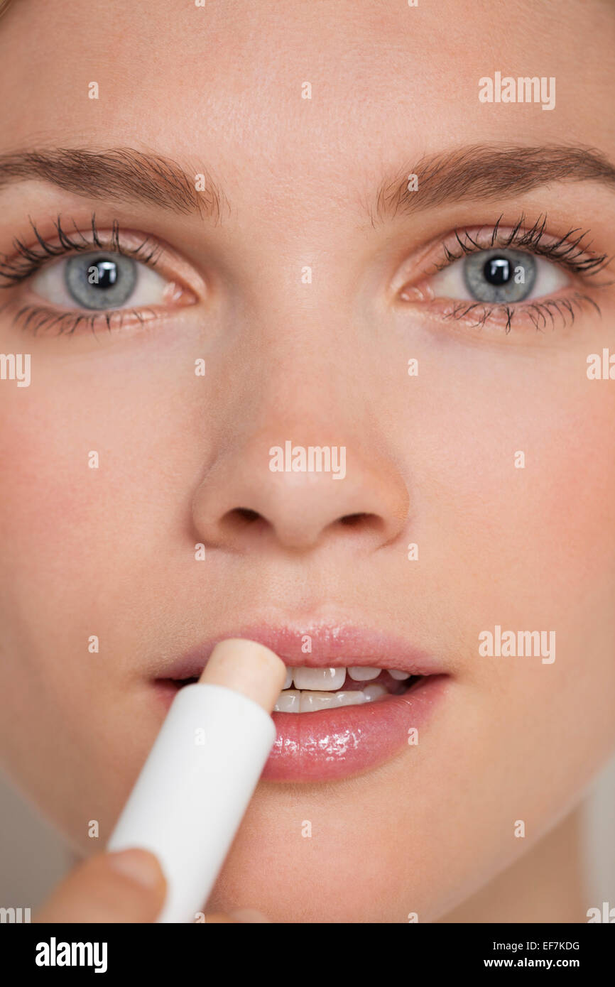 Beautiful woman applying lip balm Stock Photo - Alamy