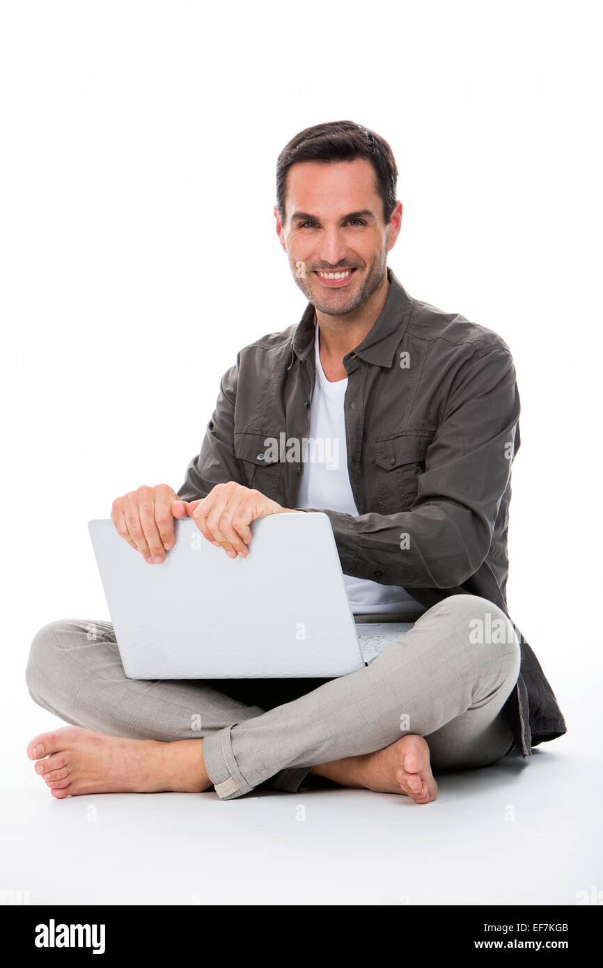 Man sitted on the floor, smiling at camera, holding his laptop with ...