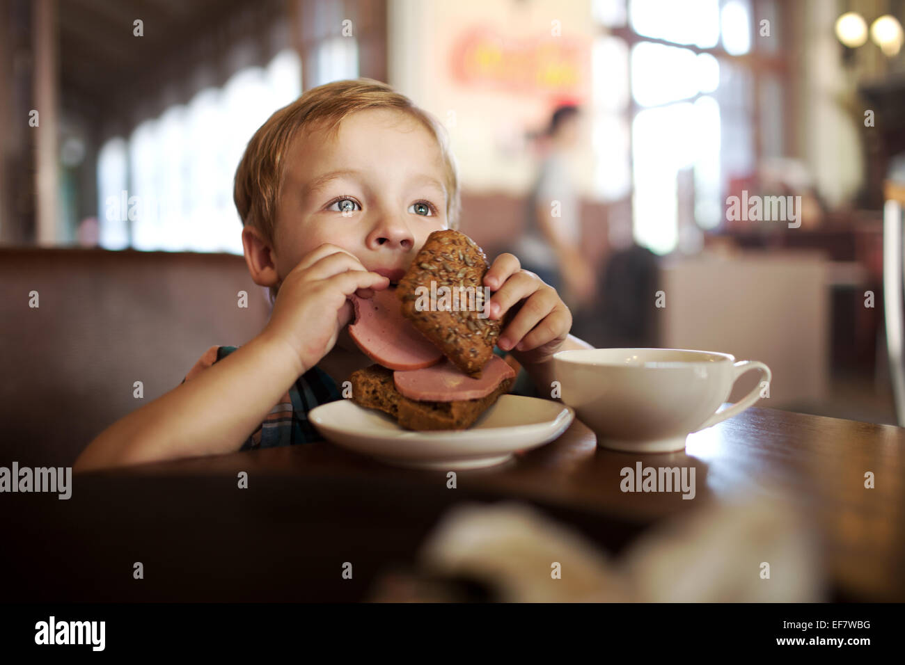 Little child having lunch with sandwich and tea in cafe Stock Photo - Alamy
