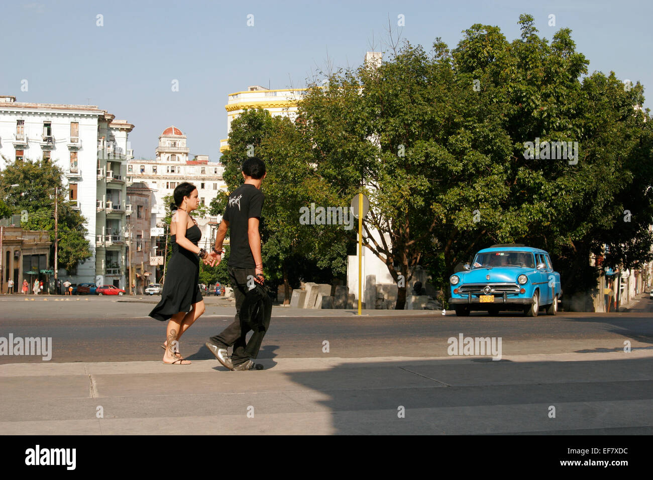 Cuban couple crossing the road in front of the blue vintage car, Havana ...
