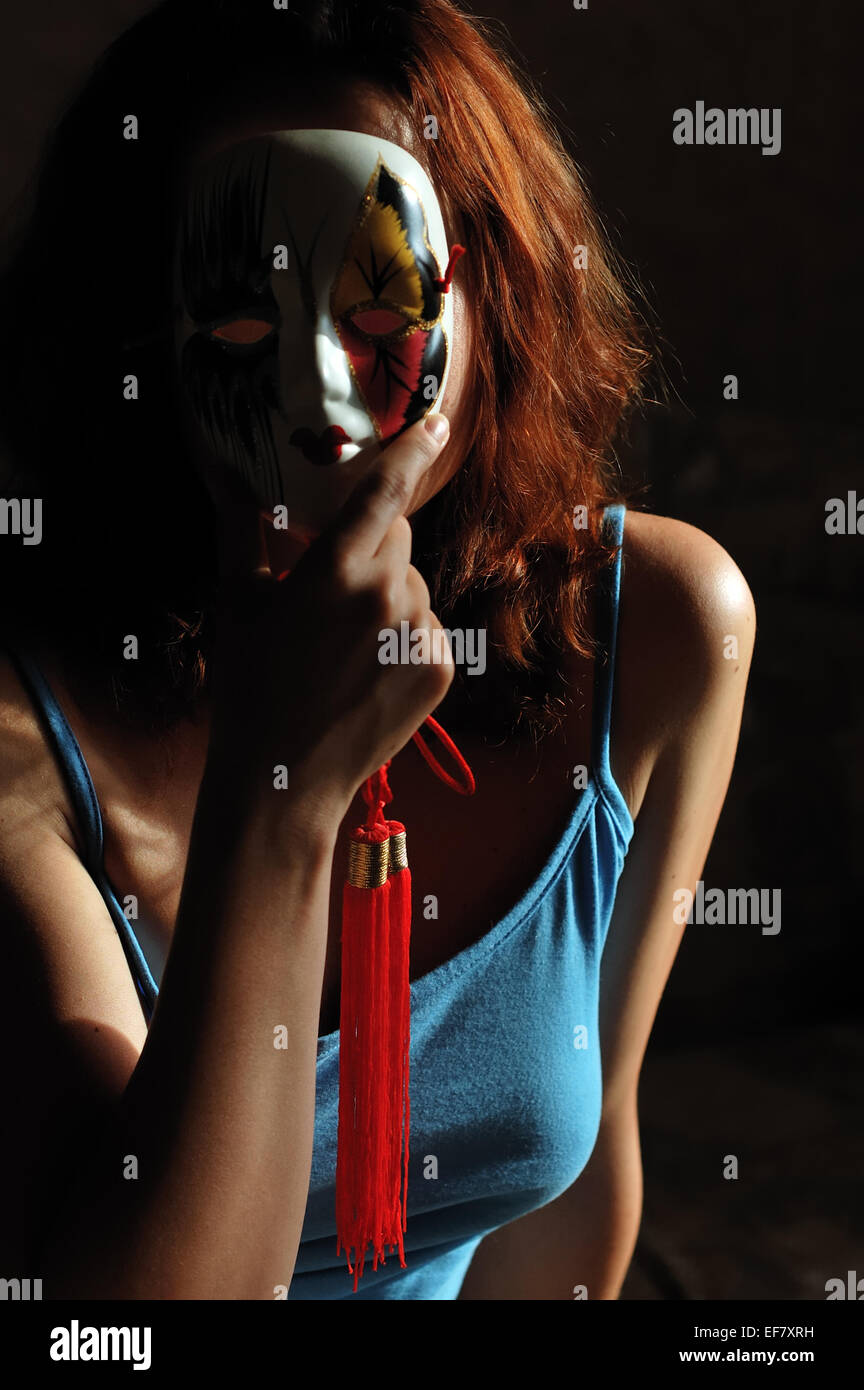 Girl with red hair behind a mask Stock Photo - Alamy