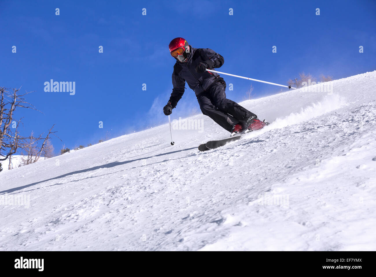 Skier with a mask on face skiing downhill in high mountains and sunny ...