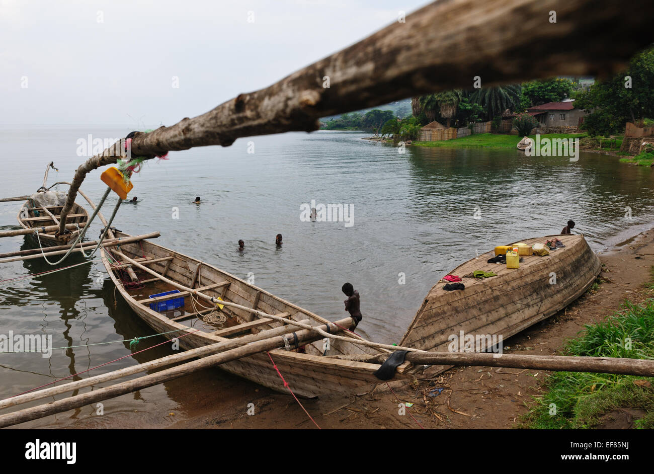 Children swimming around the specific fishing boats of Lake Kivu ...