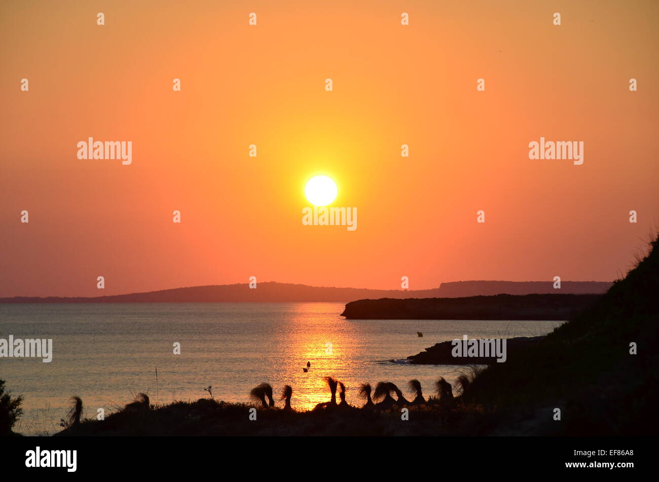 View of the sun setting from the beach at Santo Thomas, Menorca ...
