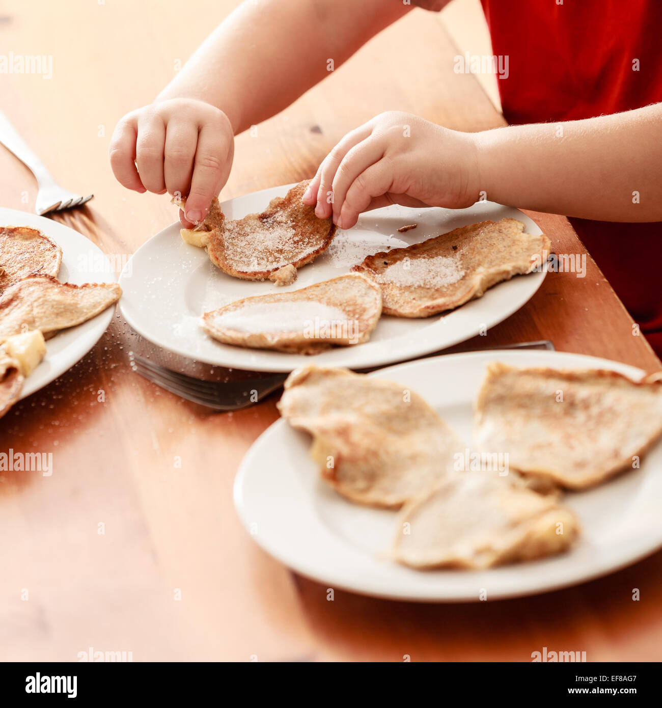 Little boy eating fried apple in pancake dough or apple fritters ...