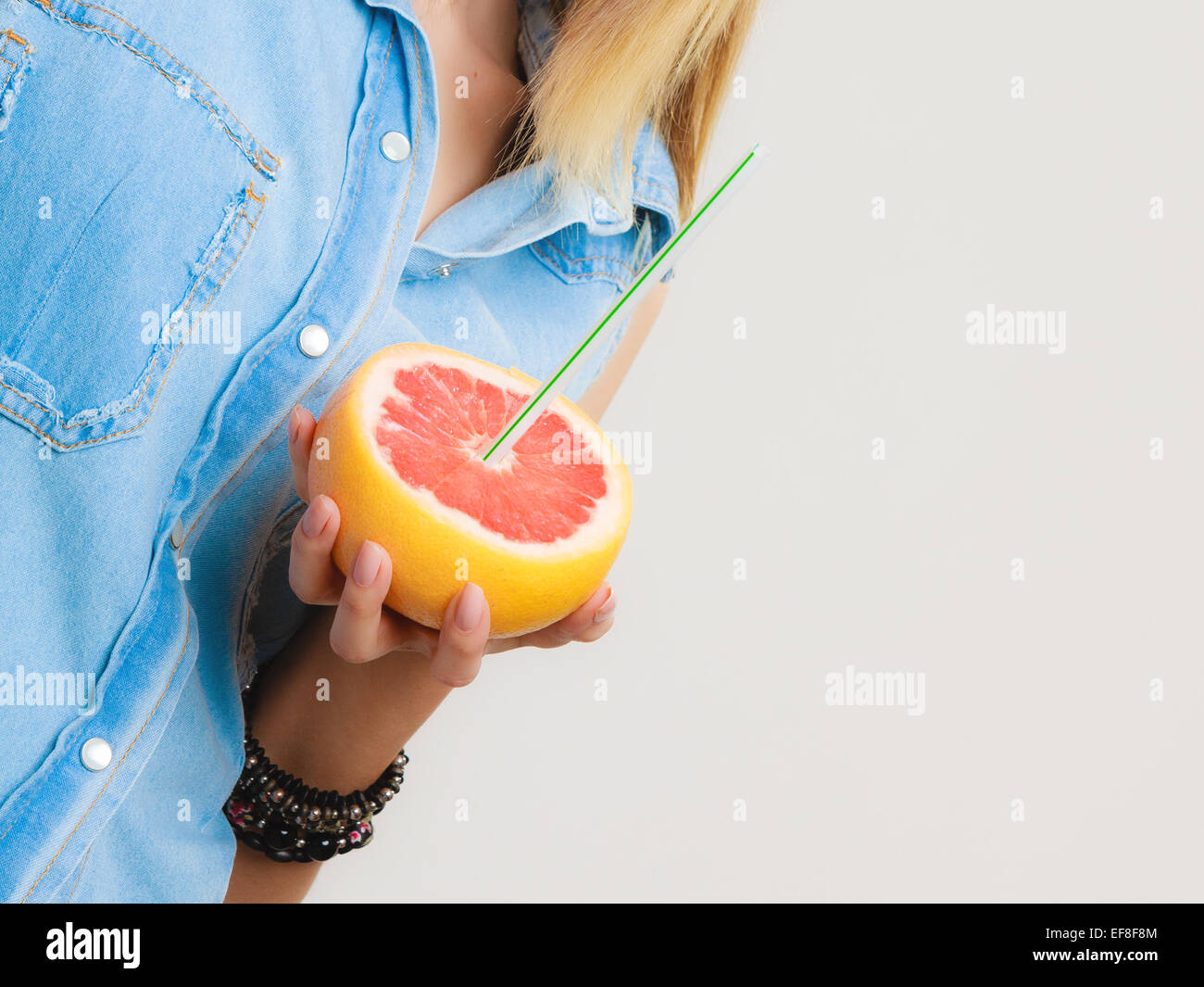 Summer vacation. Grapefruit citrus fruit with drinking straw in hand of ...