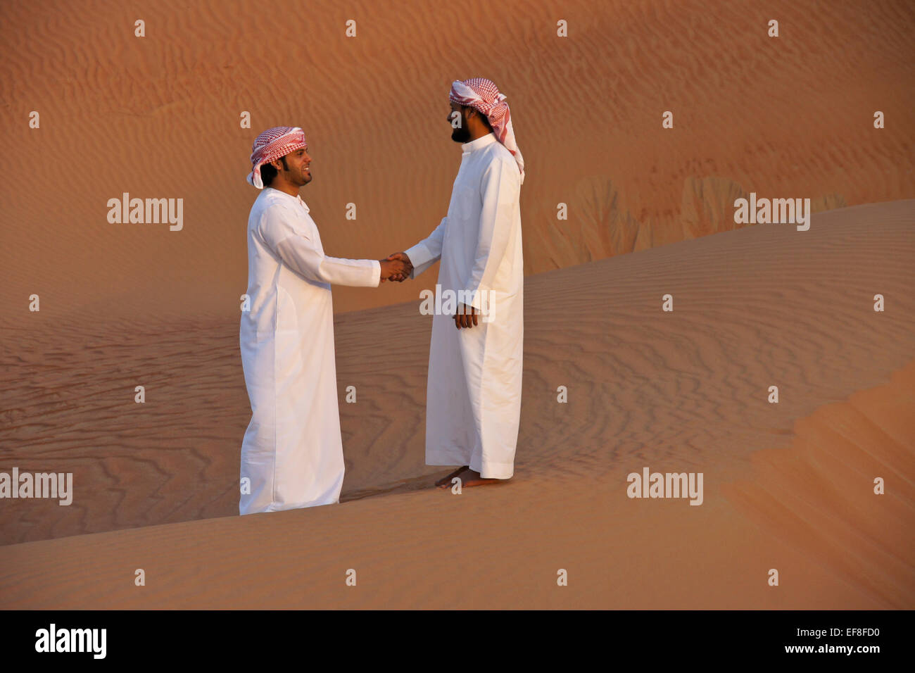 Arab men in traditional dress amid sand dunes of Liwa, Abu Dhabi, UAE ...