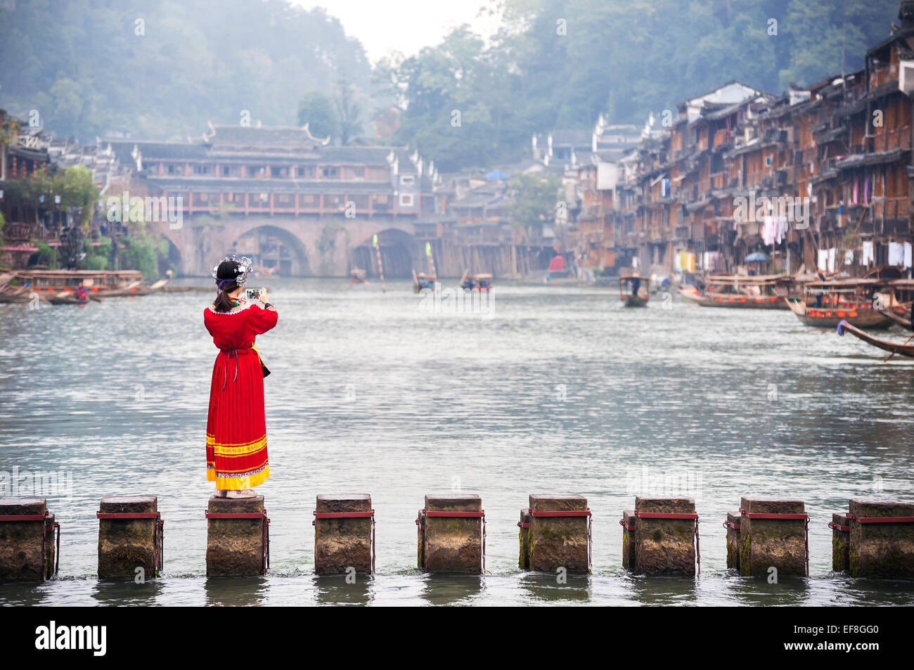 Tourist in traditional Miao costume takes a picture on the Tuojiang ...