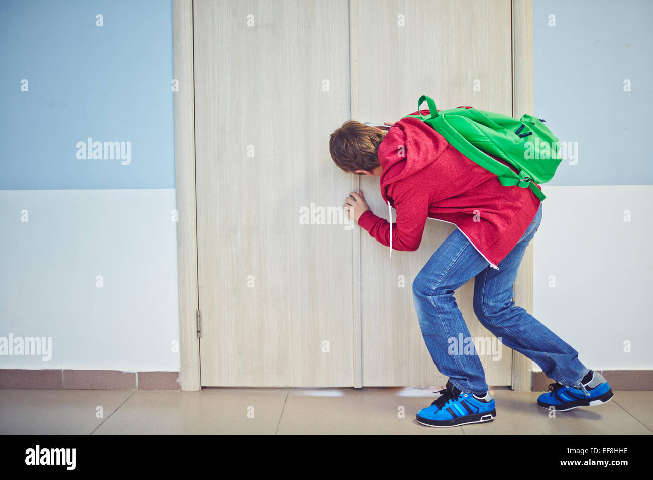 Curious learner with backpack peeping into keyhole of classroom door ...