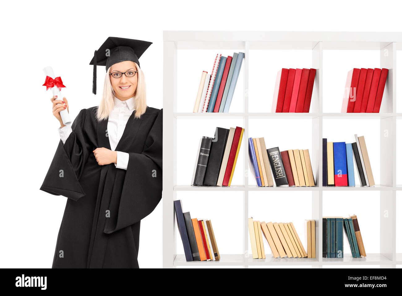 Female graduate leaning on a bookshelf isolated on white background ...