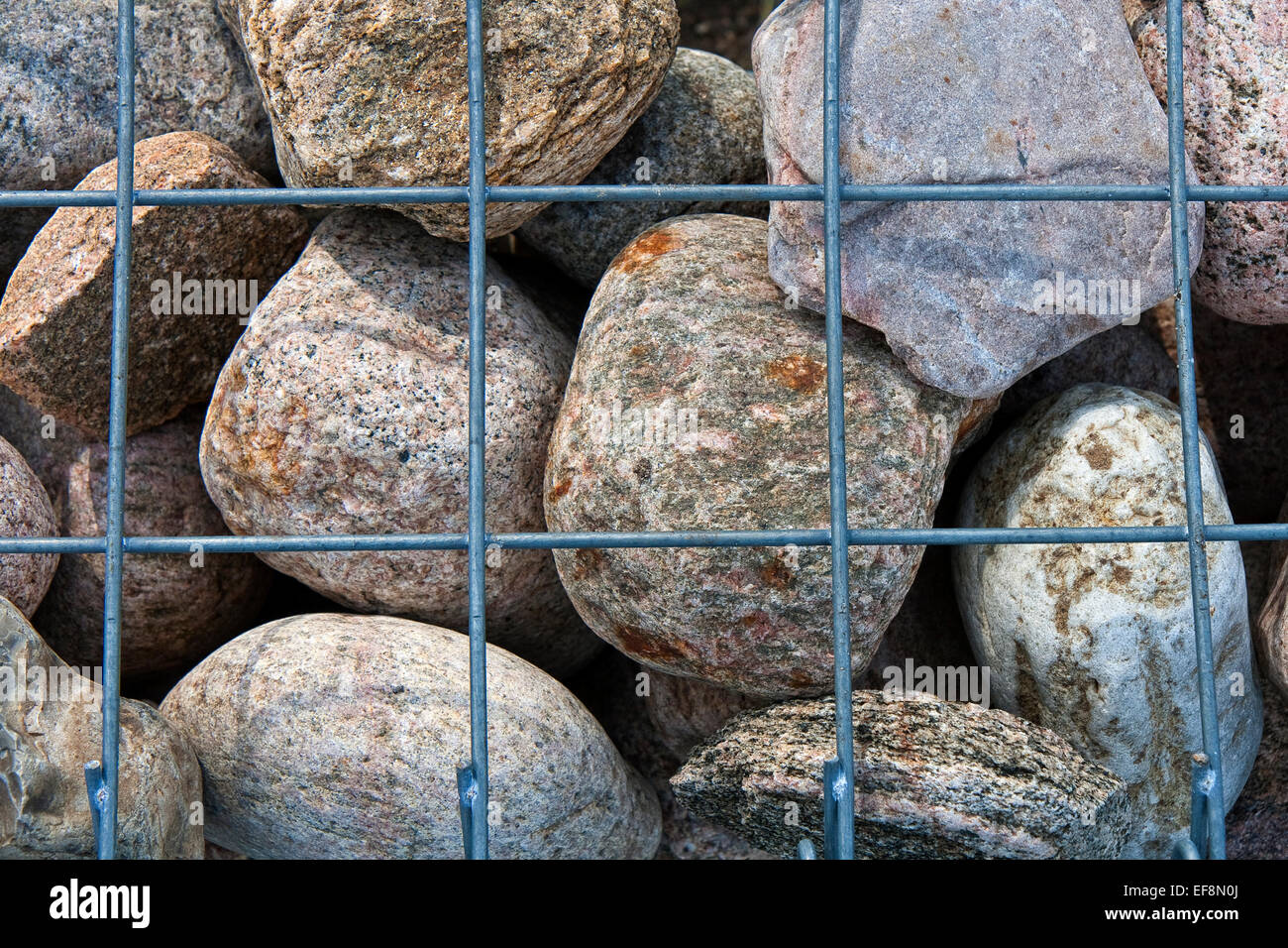 Closeup on a rock garden wall in a steel fence Stock Photo - Alamy