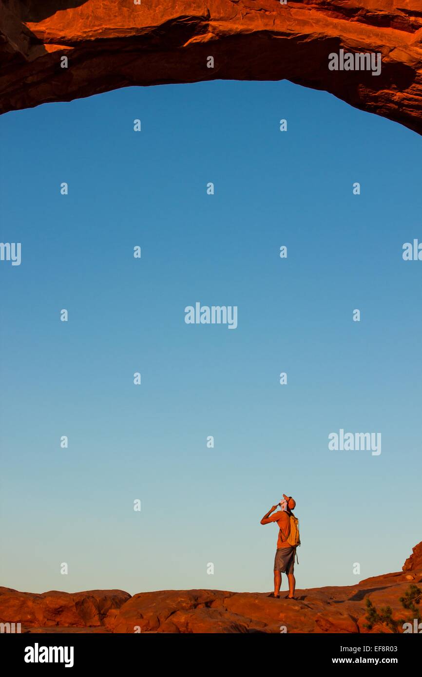 A hiker looks up at Delicate Arch a 65-foot tall freestanding natural ...